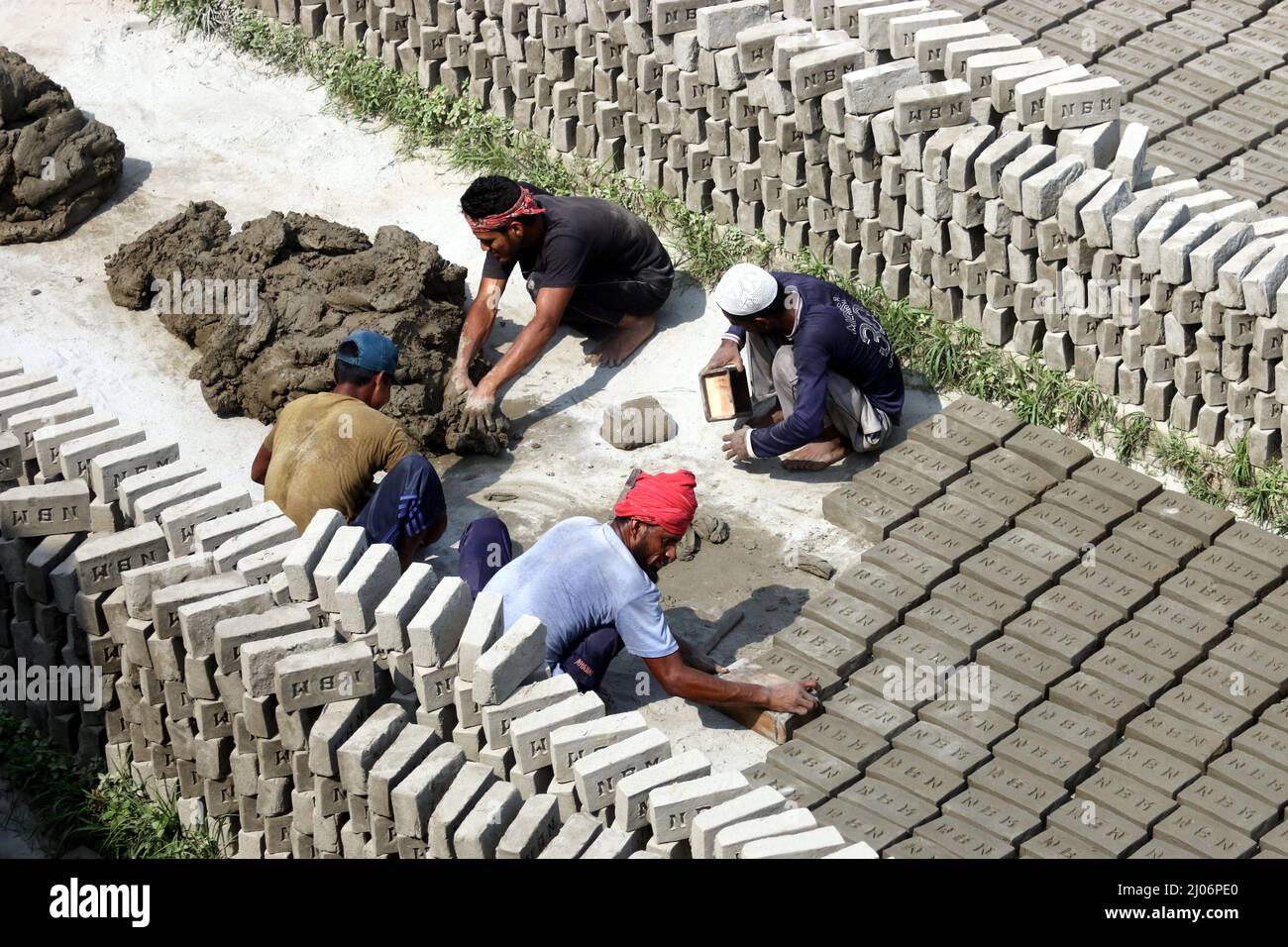 Workers transport bricks on their heads at a brick factory. Due to the ...
