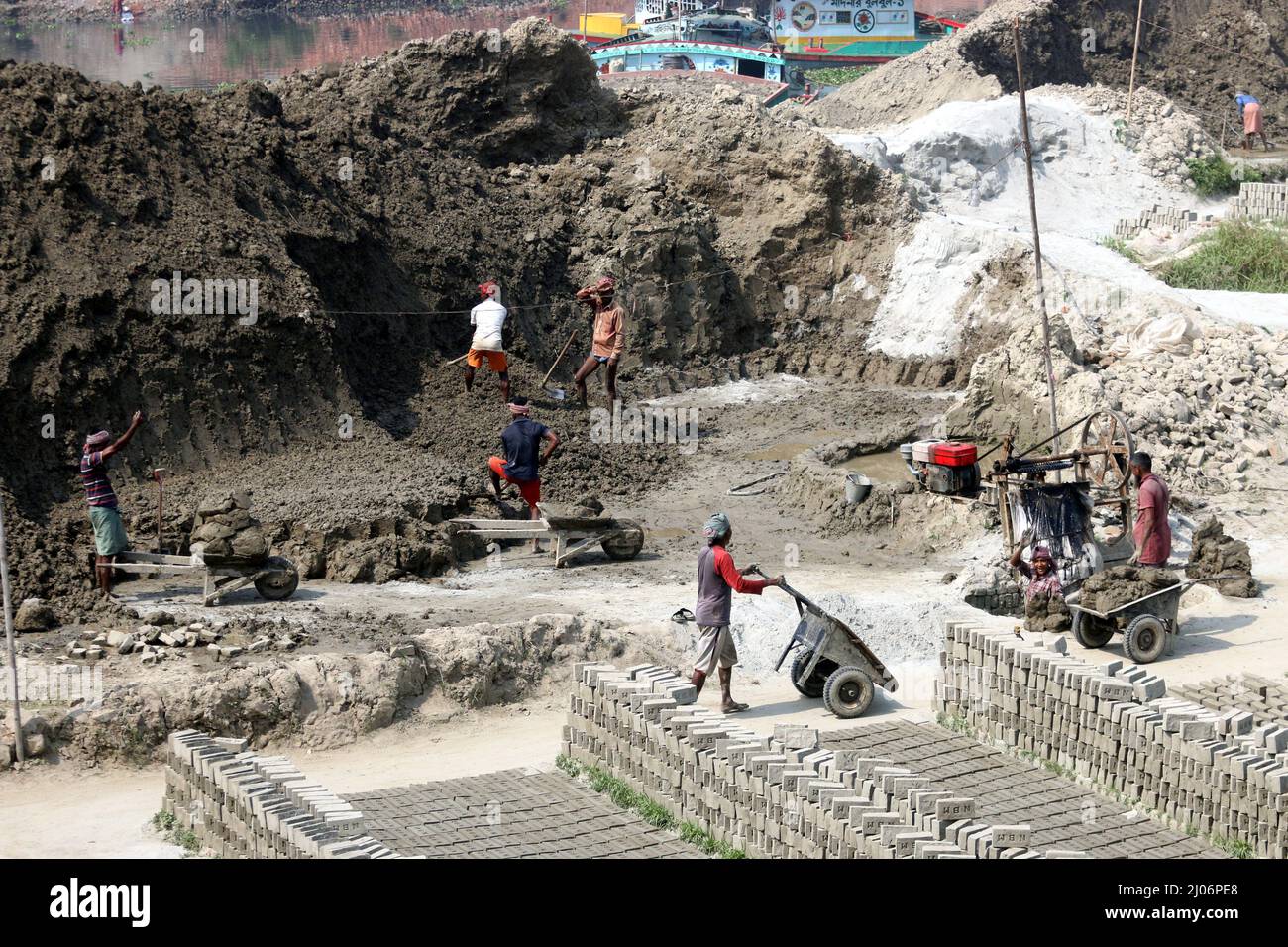 Workers transport bricks on their heads at a brick factory. Due to the ...