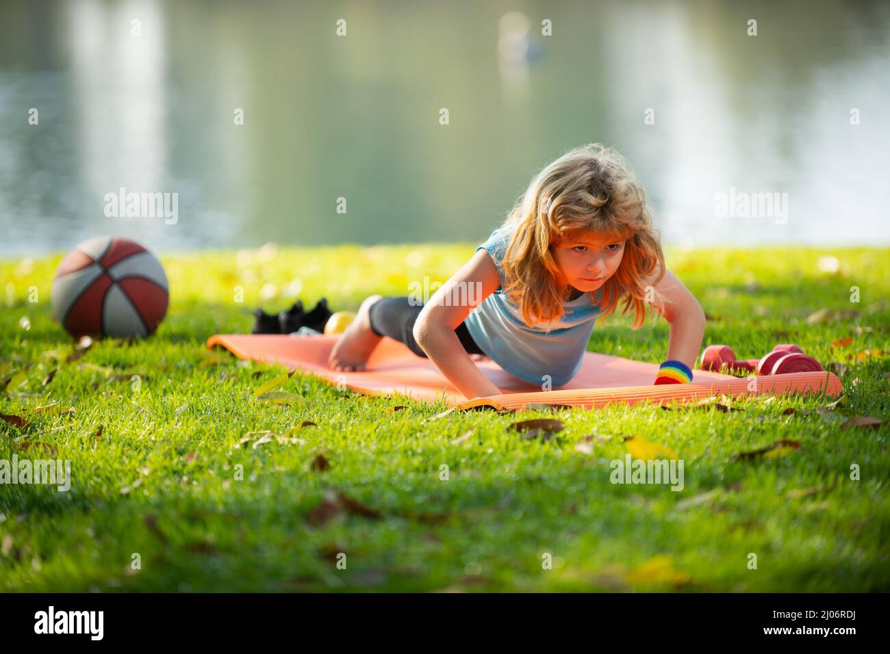 Child doing gymnastic exercises, sportive kid doing push ups on fitness ...