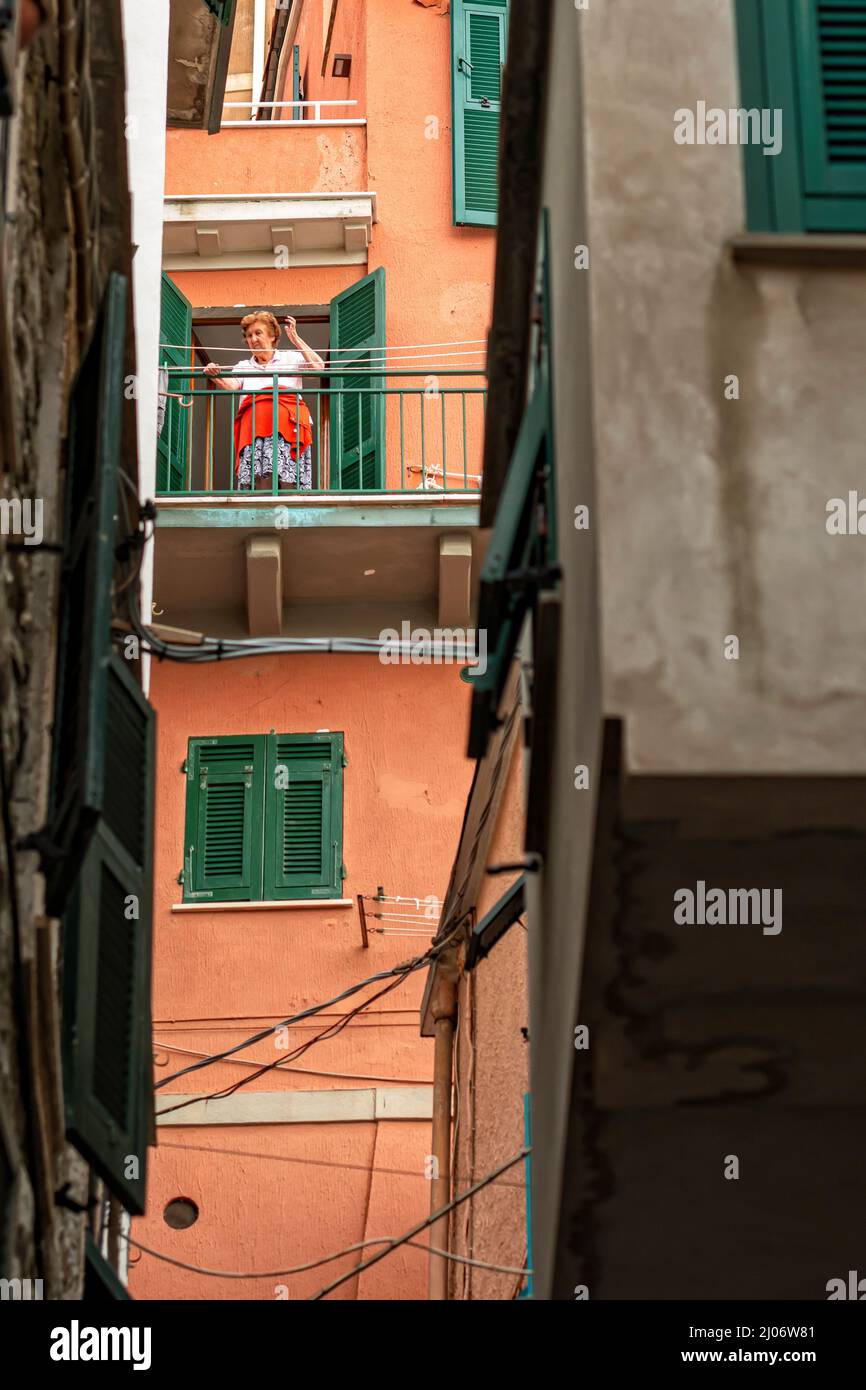Manarola, Italy - August 10, 2021: woman on the bakona of a colorful ...