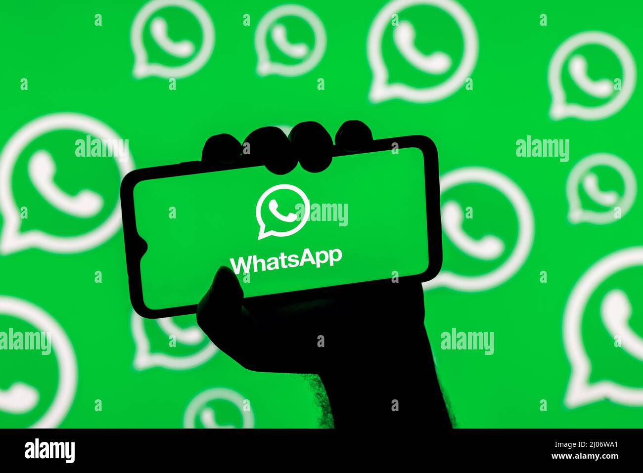 Smartphone with the Whatsapp messenger on the screen in a clenched hand ...