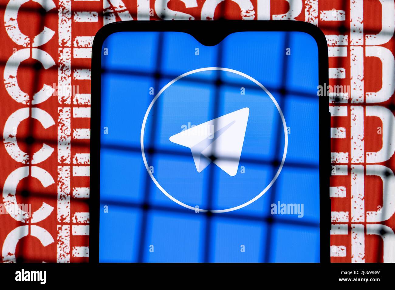 Telegram messenger logo on the smartphone screen behind the bars on the ...