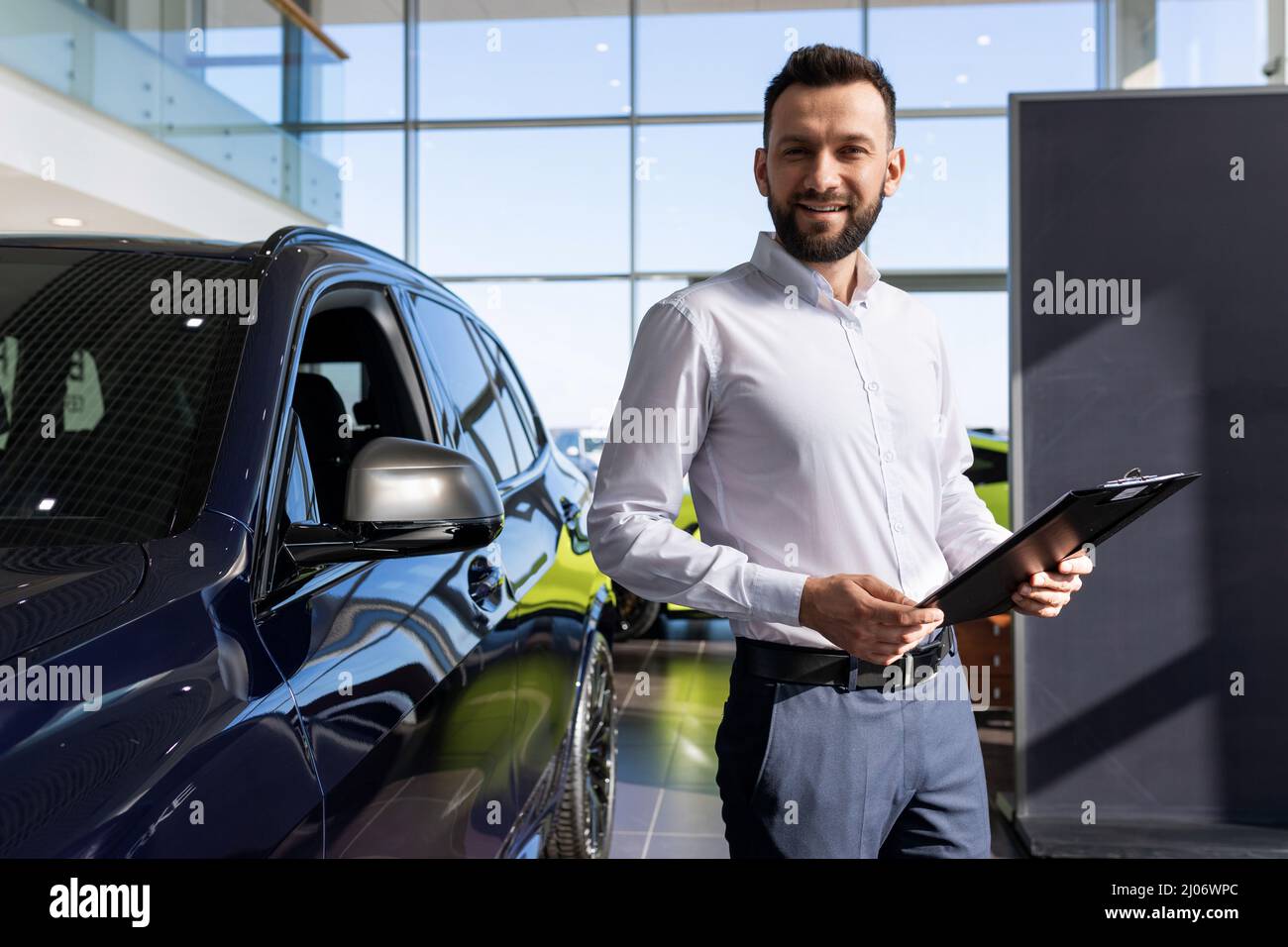 insurance company employee next to a new car in a car dealership center ...