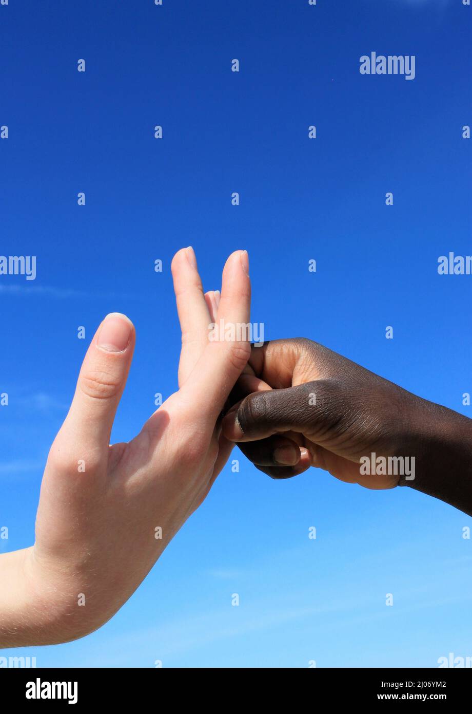 a white-skinned hand and a black-skinned hand high-five each other in ...