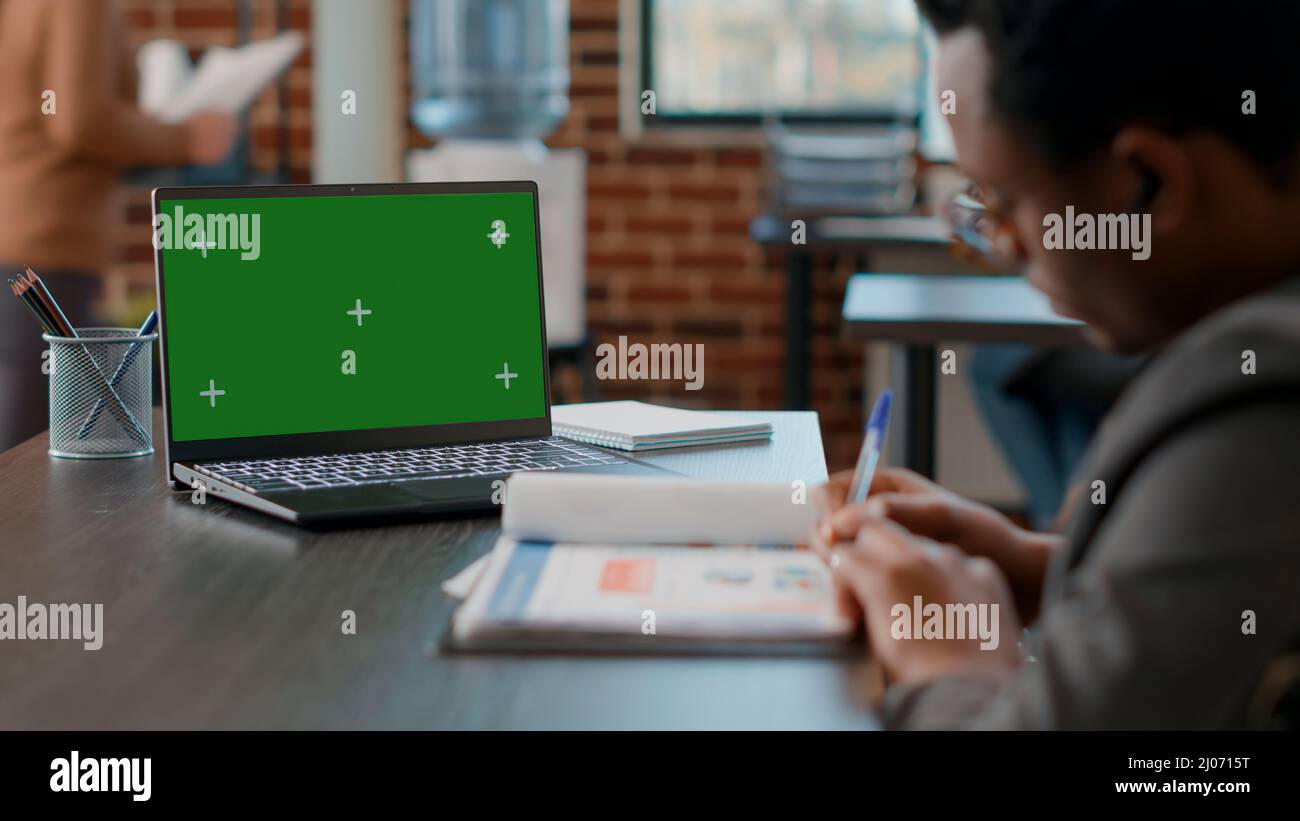 African american man looking at laptop with greenscreen in disability ...