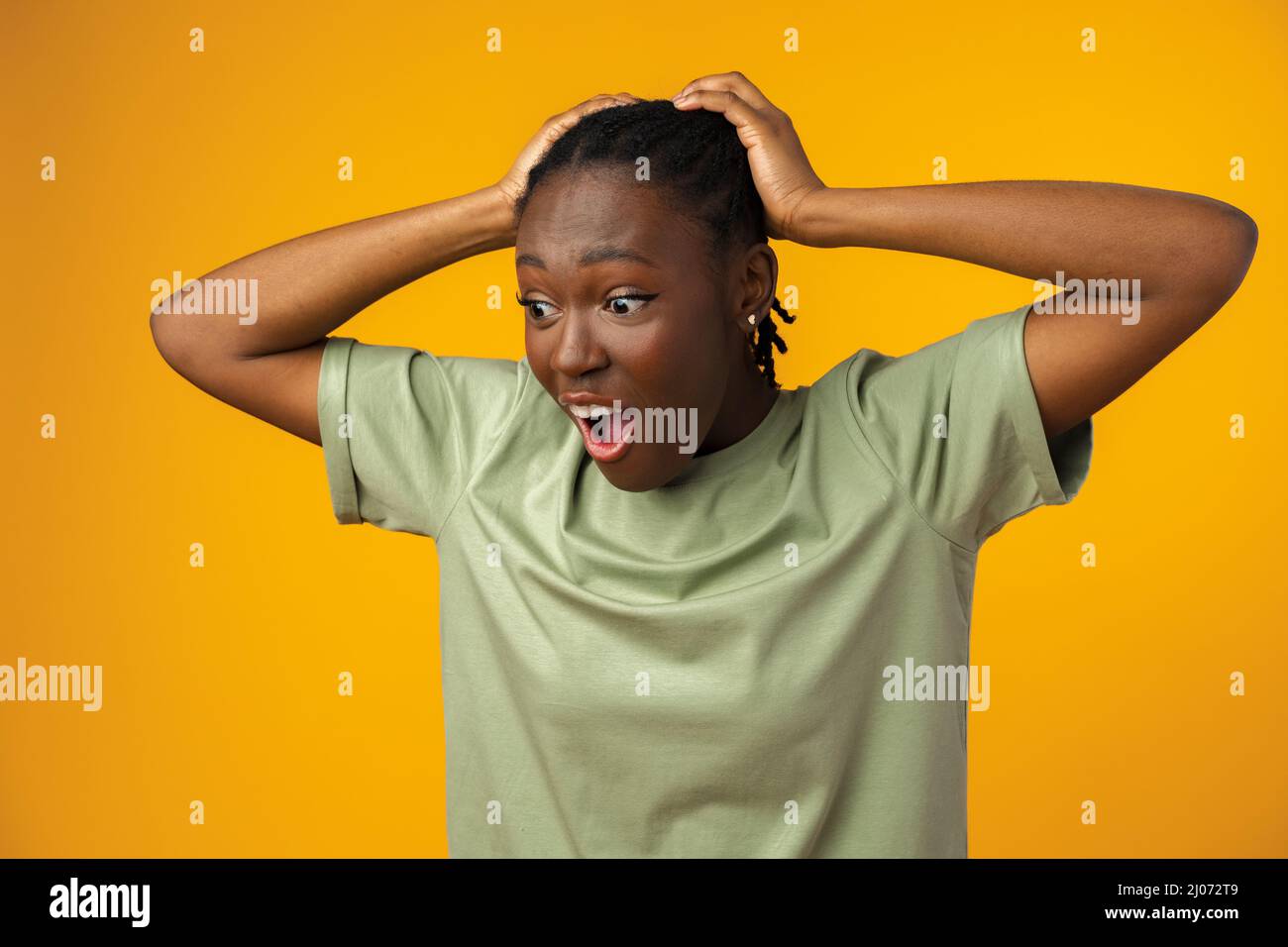 Happy african american woman looking surprised in yellow studio Stock ...