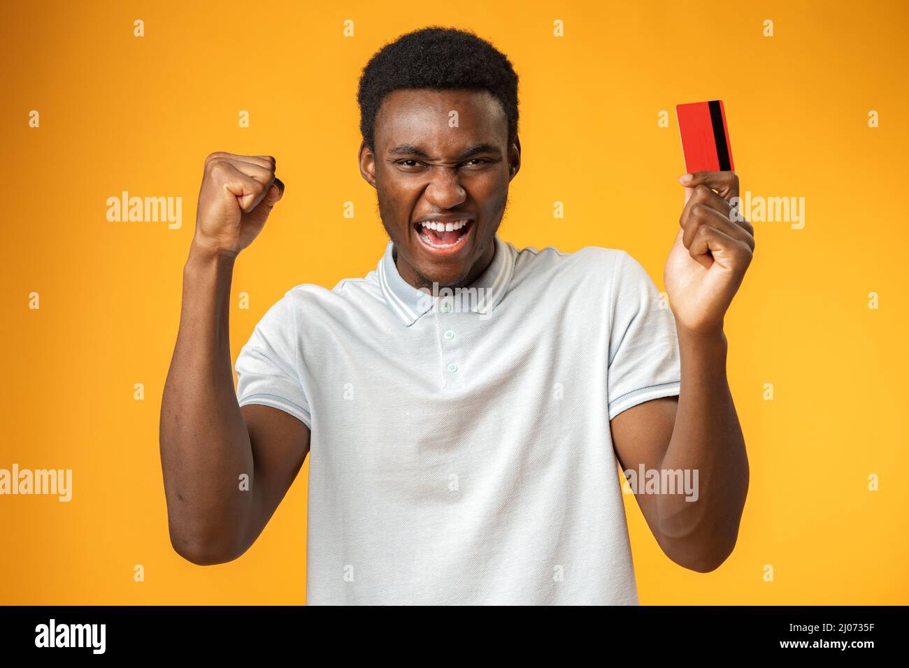 Afro american man holding red credit card against yellow background in ...