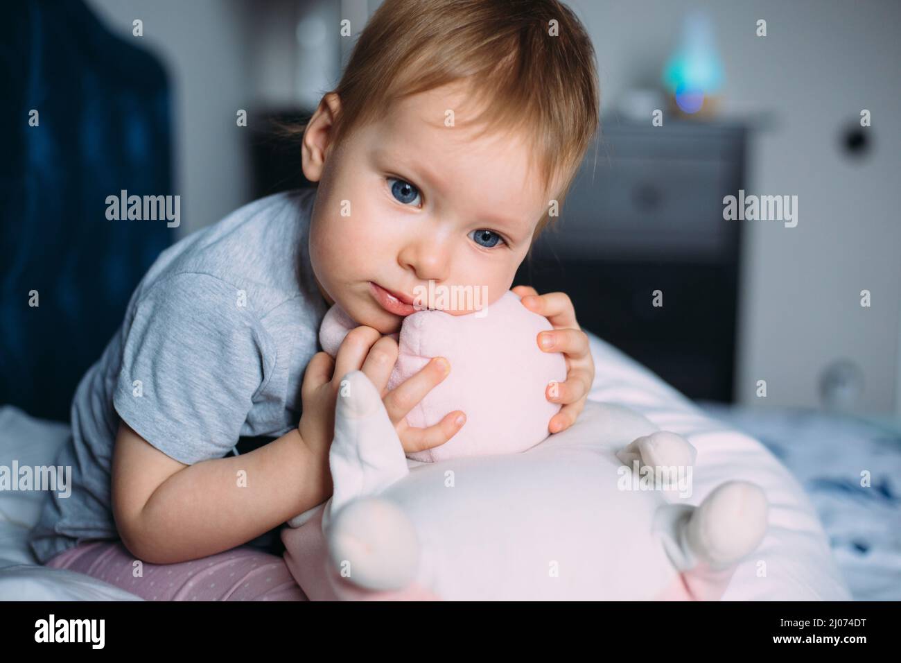 Little child is having fun, playing with soft toys on the couch at home ...