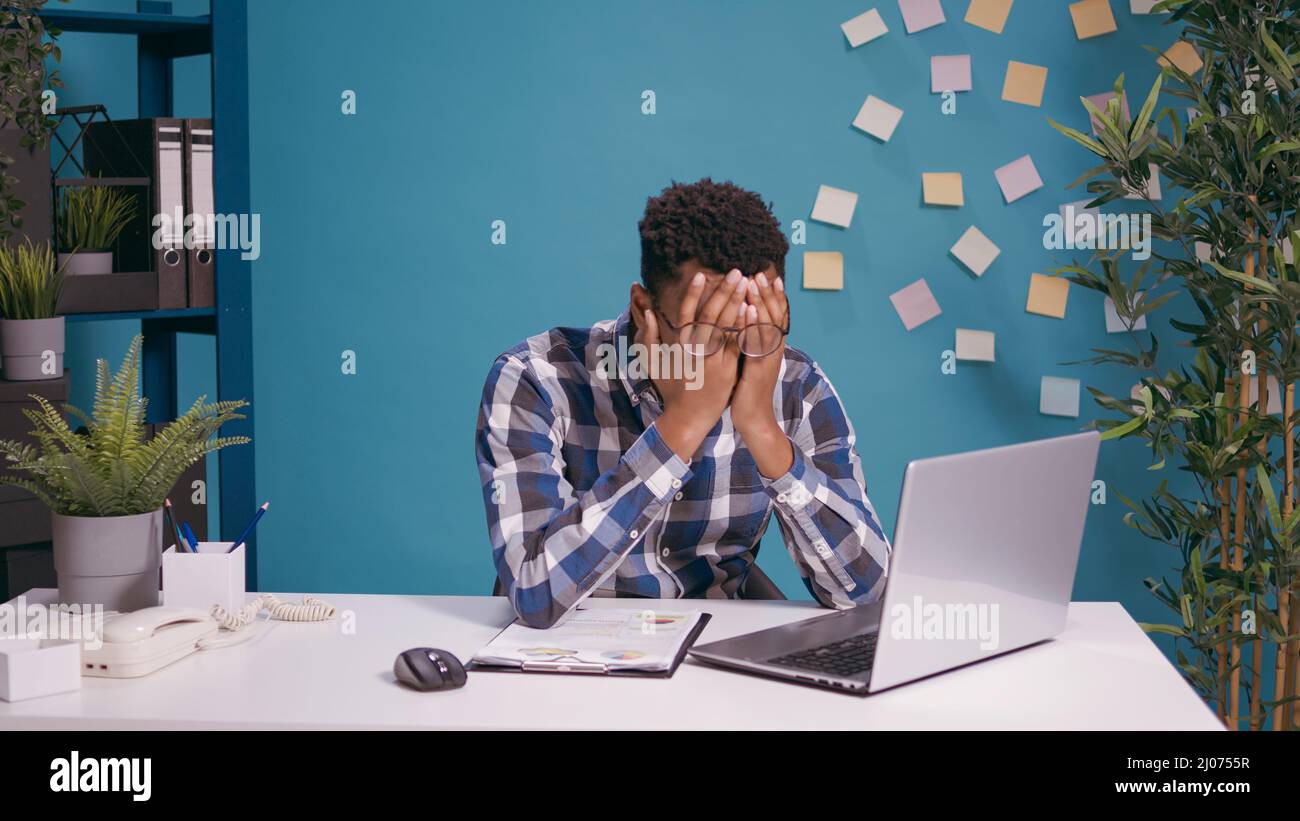 Desperate employee working on laptop computer at desk, feeling tired ...