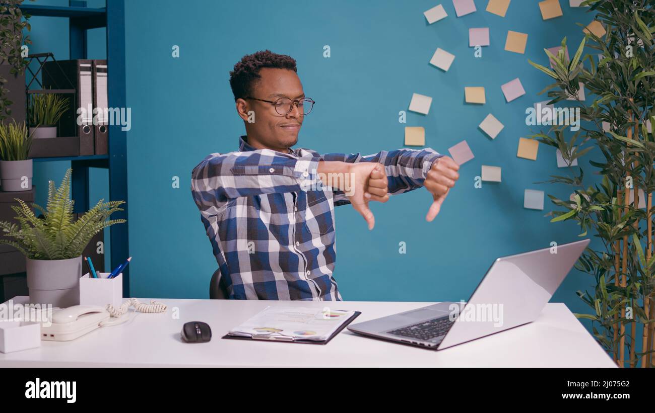Sales specialist doing thumbs down gesture in front of laptop screen ...