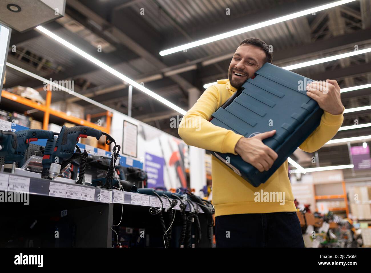 happy buyer of a new electric drill hugging the box in awe in a ...