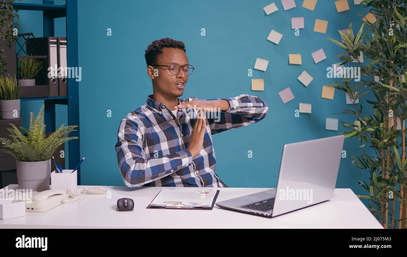 Exhausted worker doing timeout sign with hands in front of laptop ...
