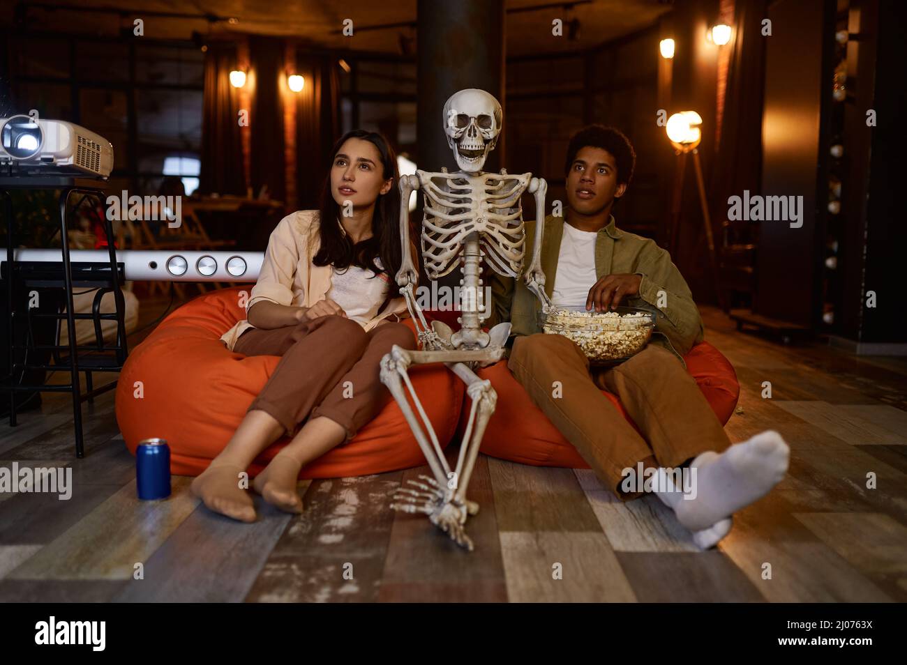 Funny couple and skeleton watching studio projector Stock Photo - Alamy