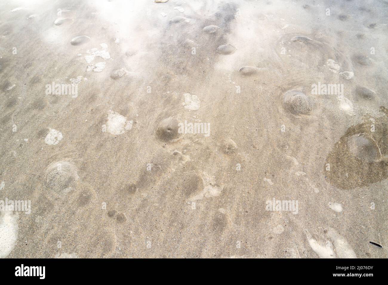 Bubbles in the sand showing that the tide is coming in Stock Photo - Alamy