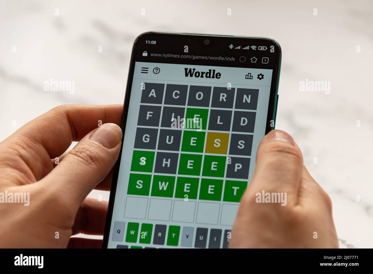 Person's hands holding a phone playing the Wordle game on NYTimes.com ...