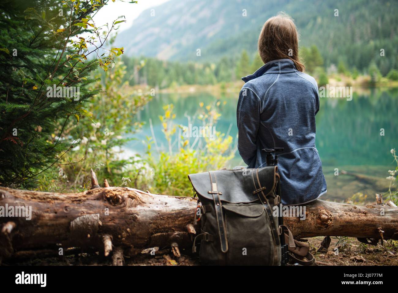 Tourist young woman with backpack siting near lake on mountain ...