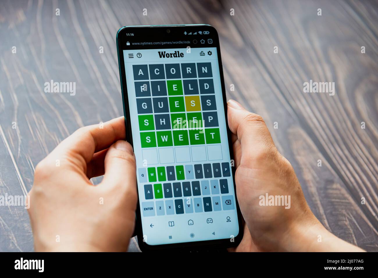 Person's hands holding a phone playing the Wordle game on NYTimes.com ...