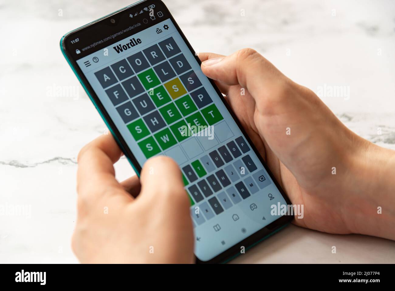 Person's hands holding a phone playing the Wordle game on the NYTimes ...