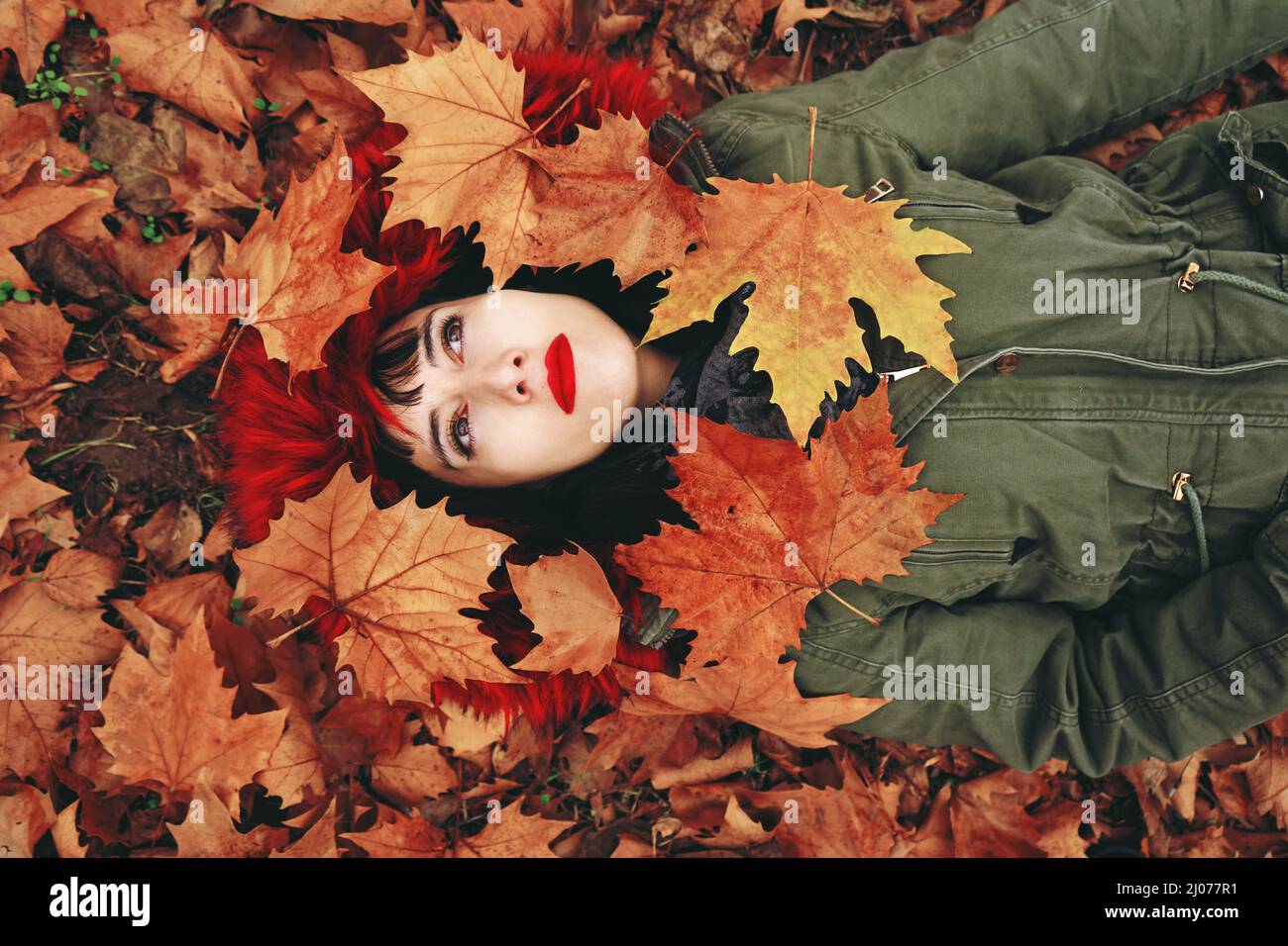 Young woman lying down in the floor full of autumn leaves Stock Photo ...