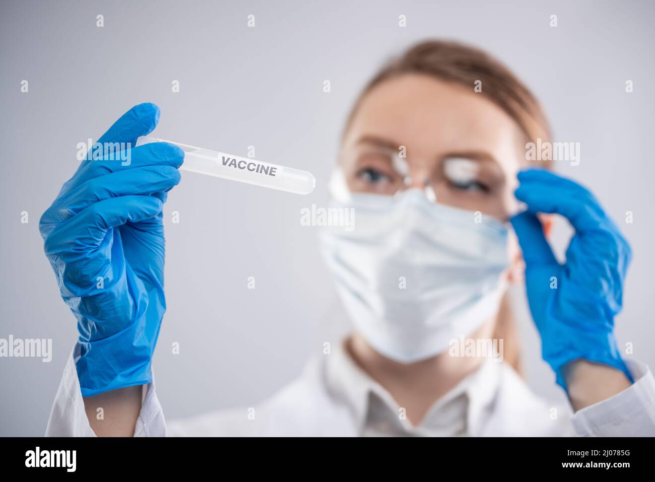 Female microbiologist in protective gloves and face mask look at ...