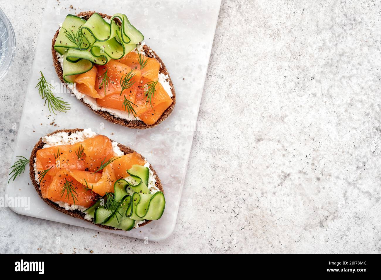 Rye bread open sandwiches with salted salmon and cucumber on a white ...