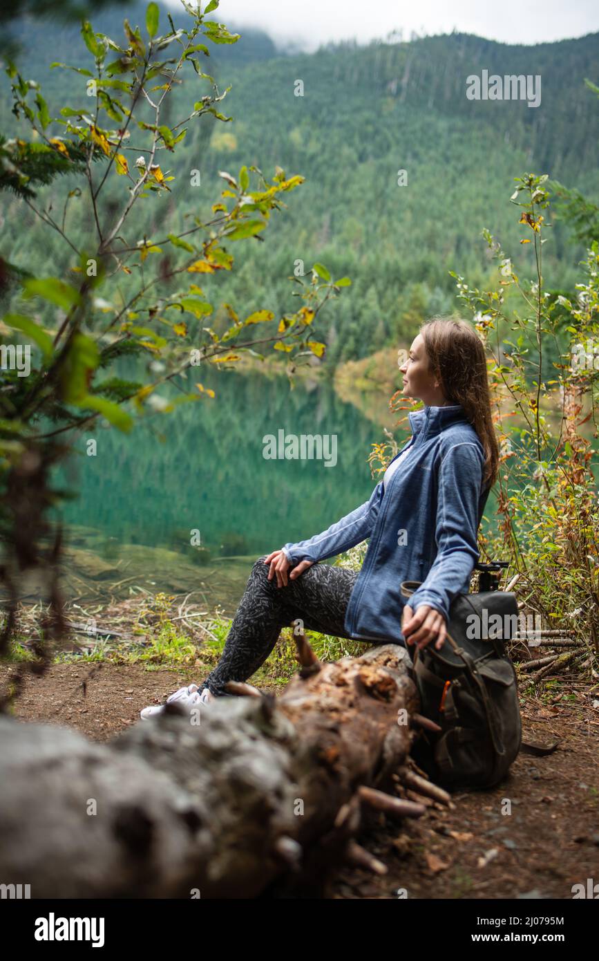 Side view of tourist beautiful woman with backpack siting near lake on ...