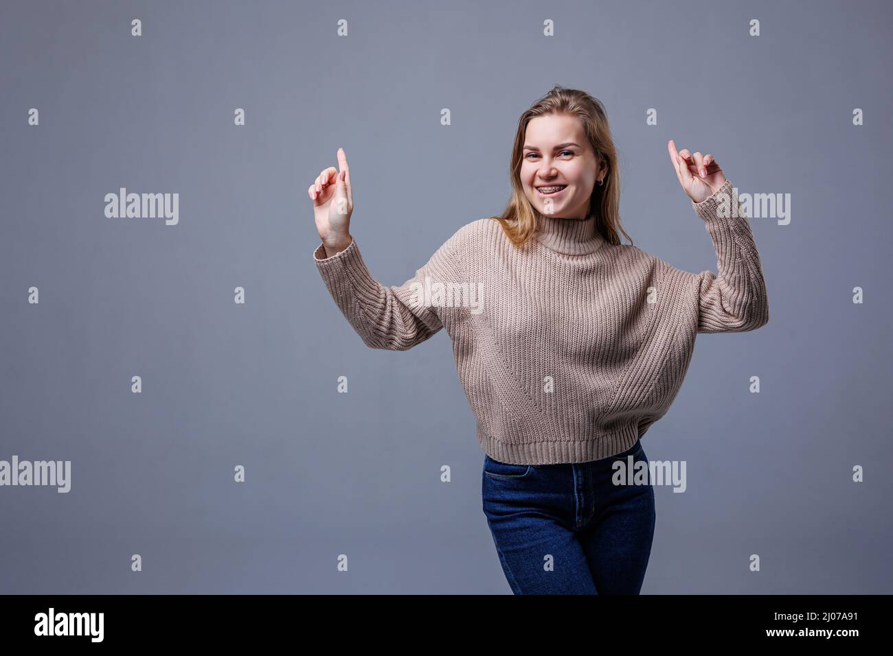 Portrait of a cheerful young woman, isolated gray wall background ...