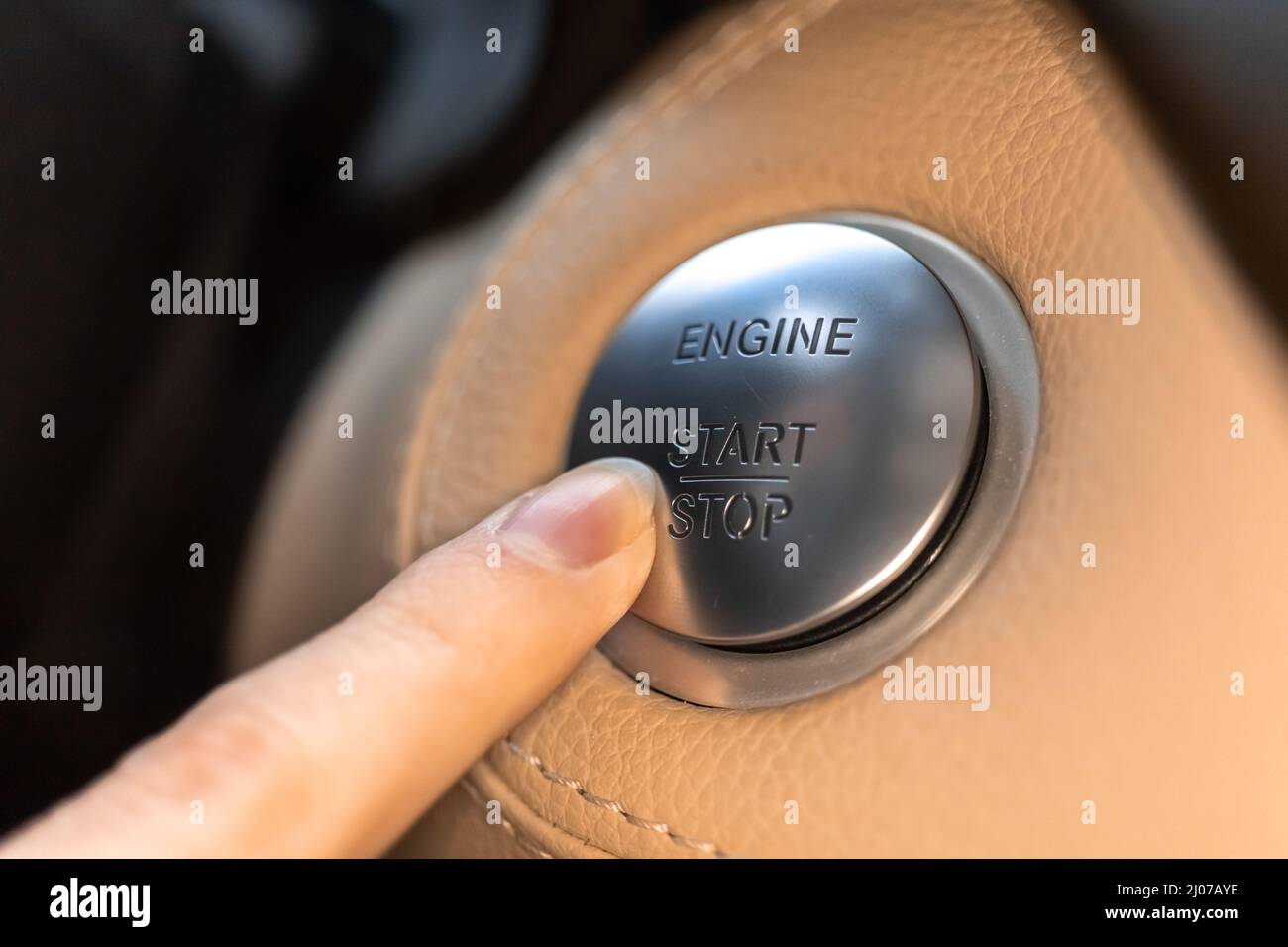 Woman pressing engine start and stop button in luxury sport car close ...