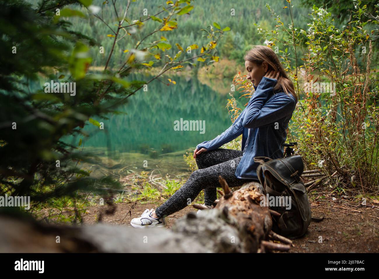 Tired tourist beautiful woman with backpack siting near lake on ...