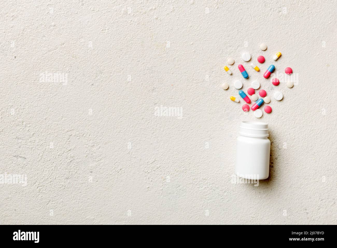 Multicolored pills and capsules in plastic bottle on Colored background ...