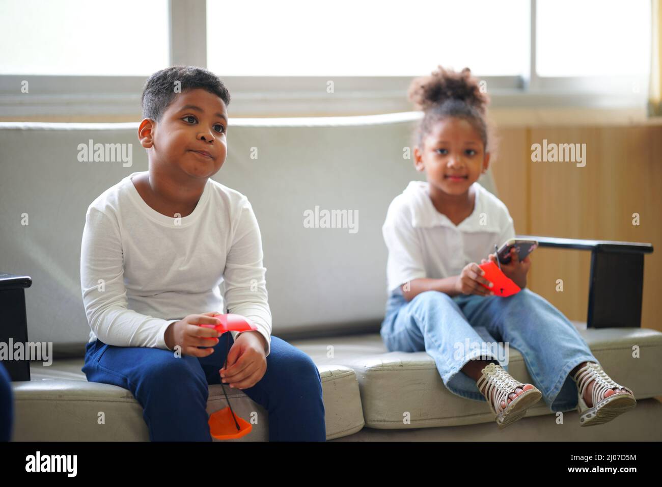 Portrait of african american kid sitting on sofa with mobile divice ...