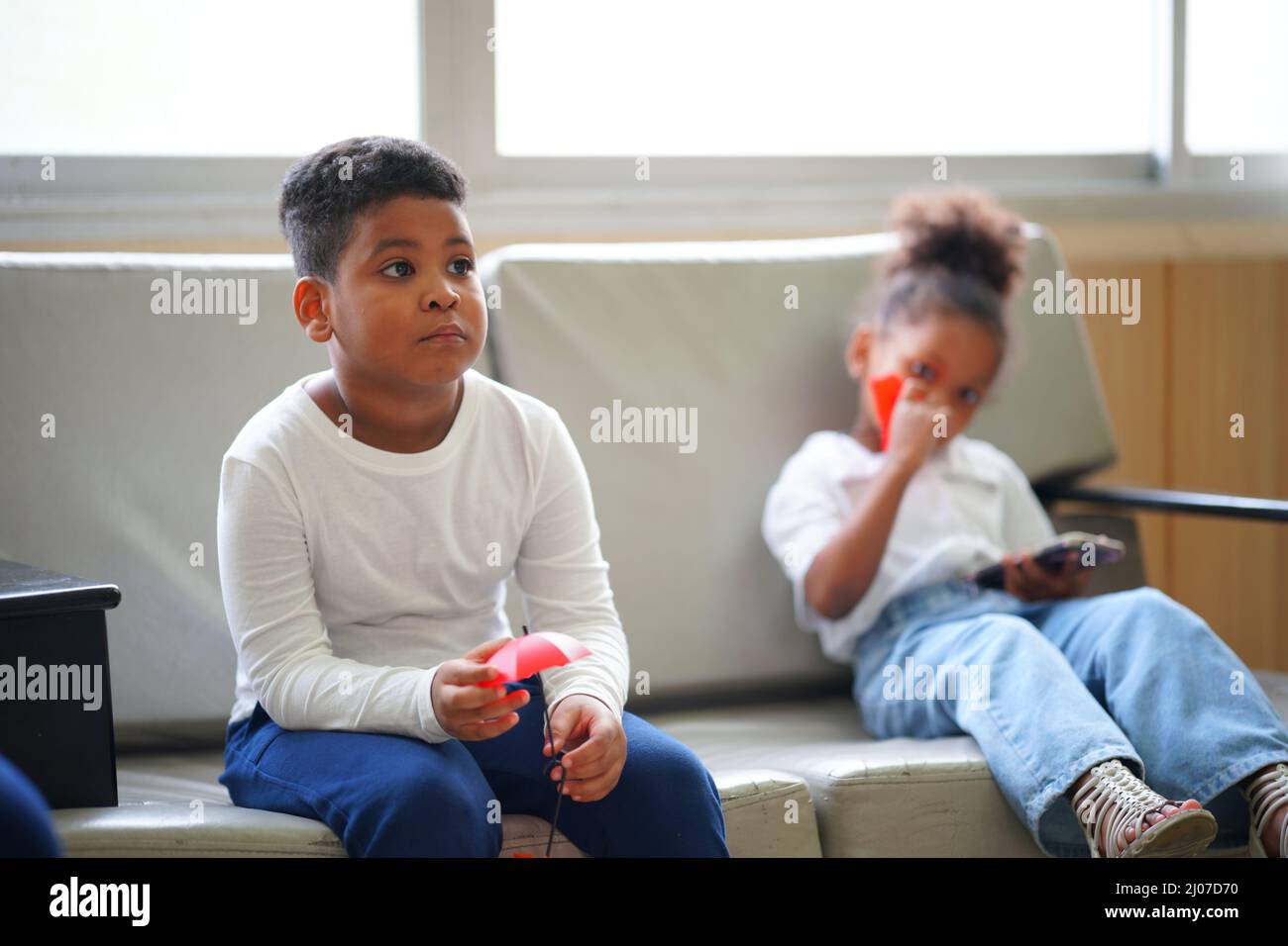 Portrait of african american kid sitting on sofa with mobile divice ...