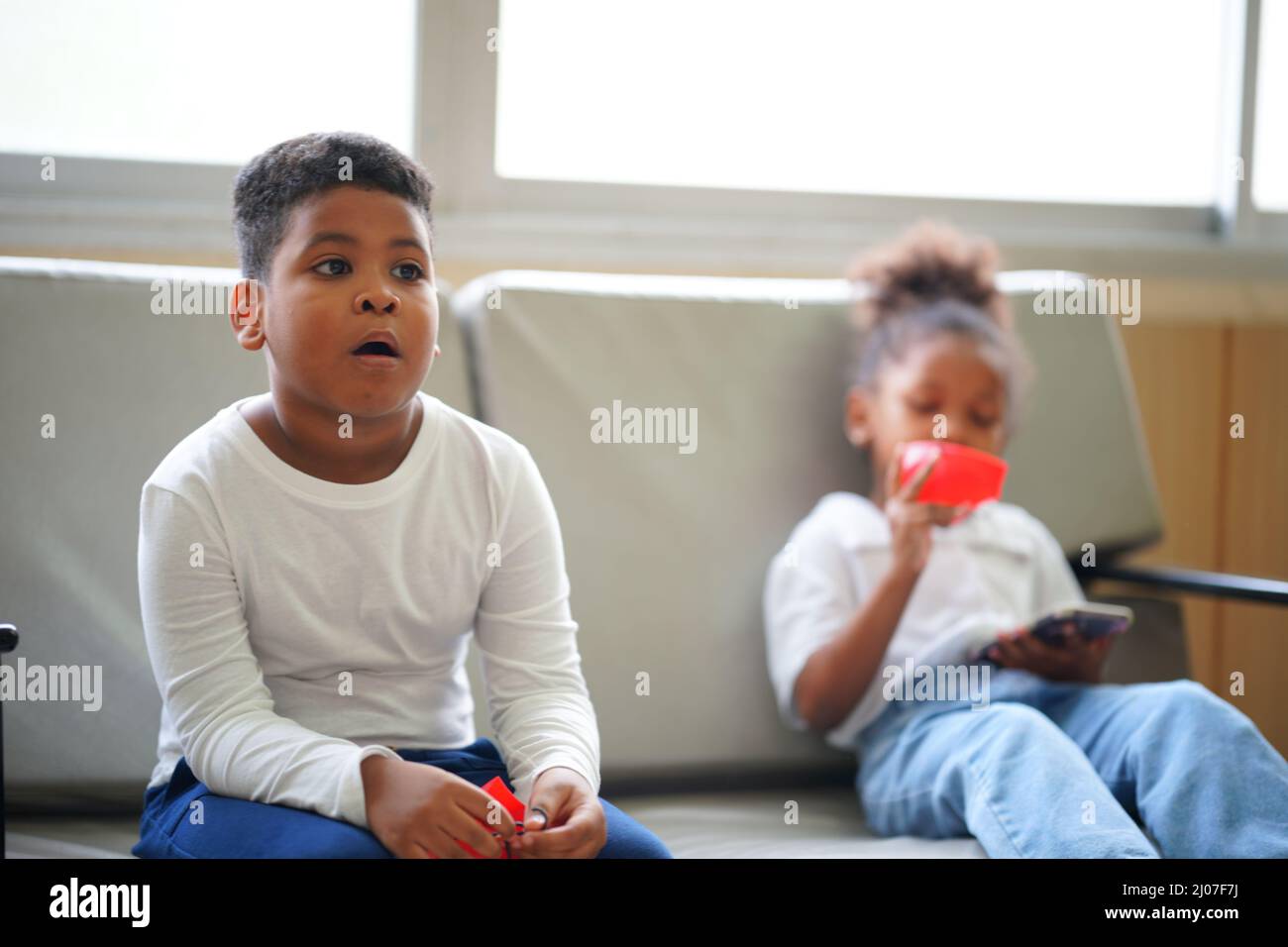 Portrait of african american kid sitting on sofa with mobile divice ...