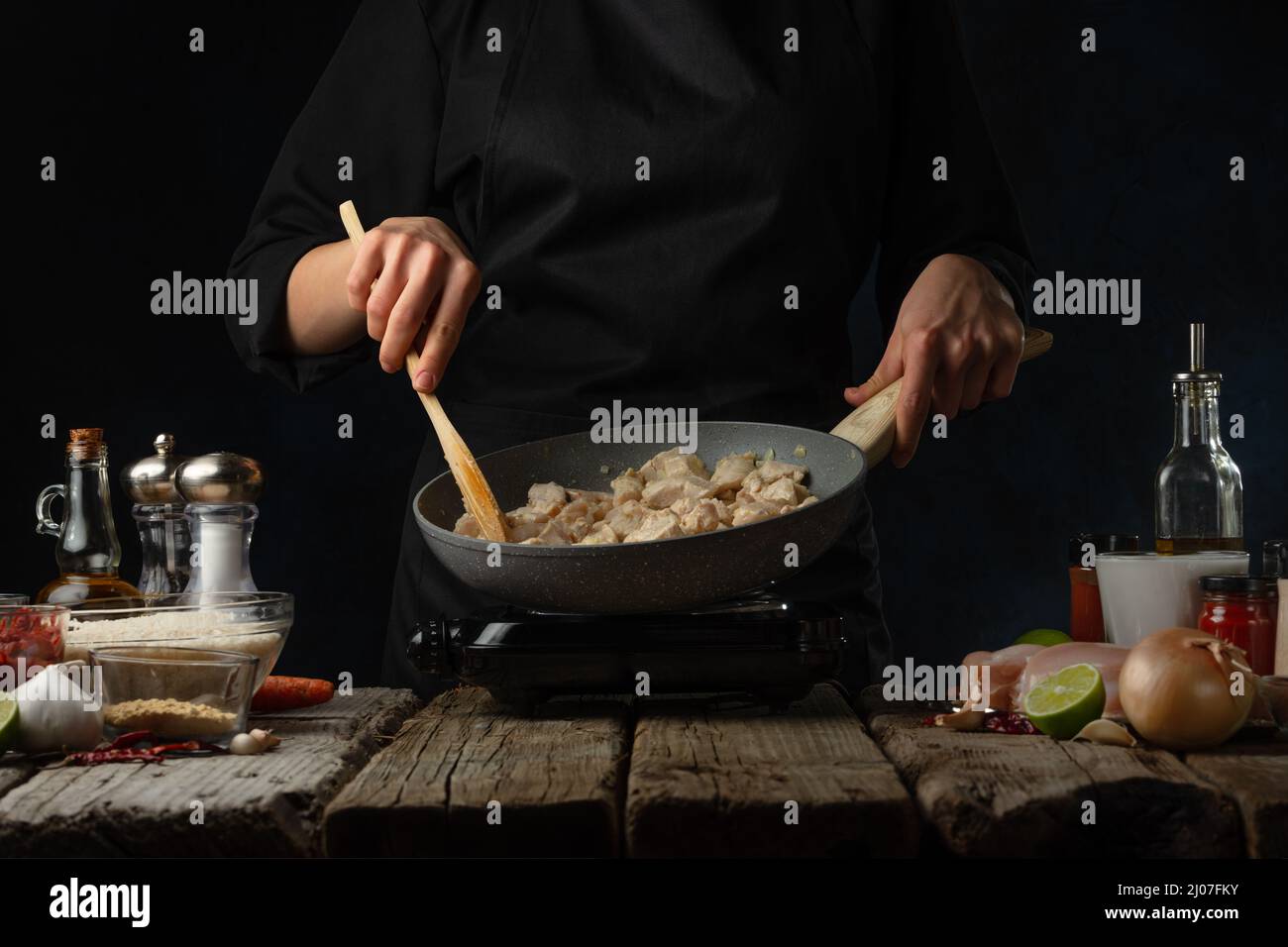 Professional chef stir frying chicken fillet in the pan. Backstage of ...