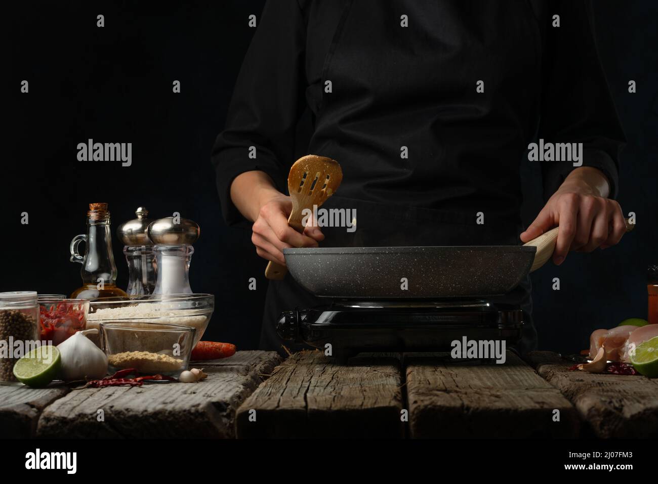 Professional chef cooking traditional Indian chicken curry on dark blue ...