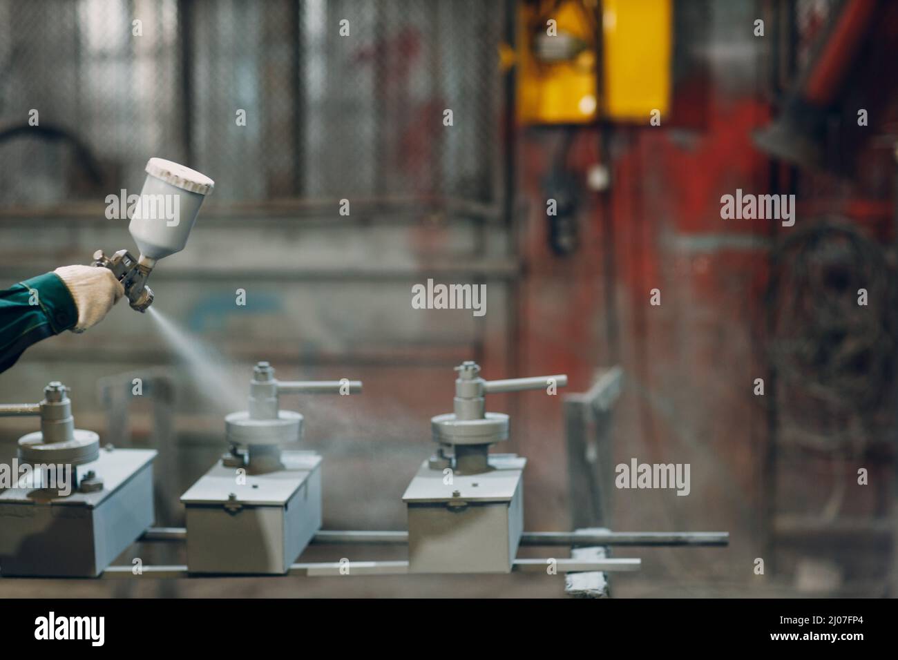 Powder paint coating of metal parts. Worker man in a protective suit ...