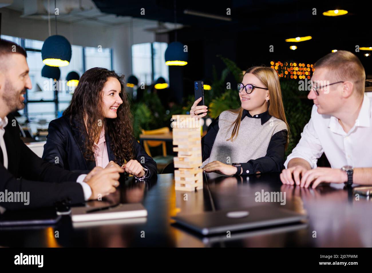 Businessmen are playing Jenga games. They sit in the office and play ...