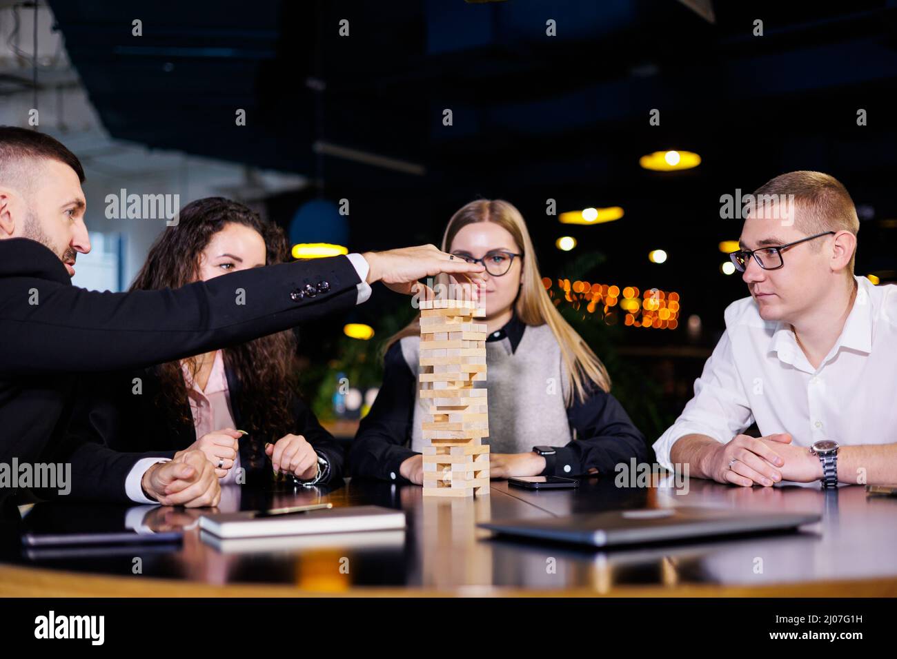 Businessmen are playing Jenga games. They sit in the office and play ...