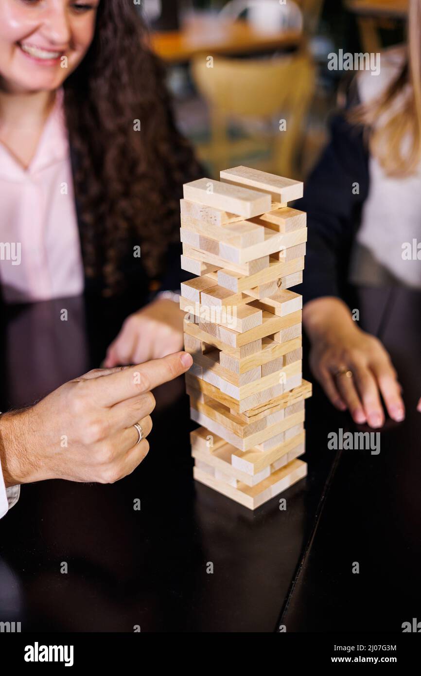 Friends build a tower from wooden blocks on the table, teamwork concept ...