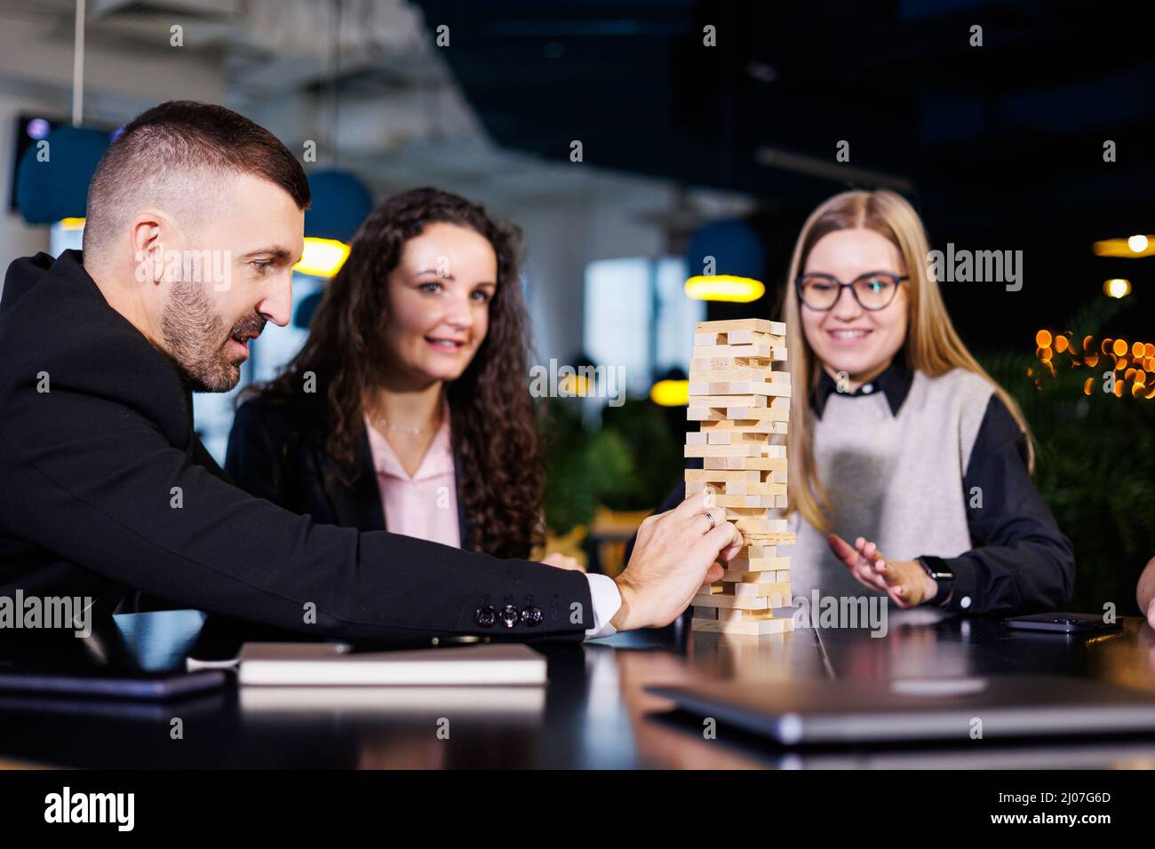 Businessmen are playing Jenga games. They sit in the office and play ...