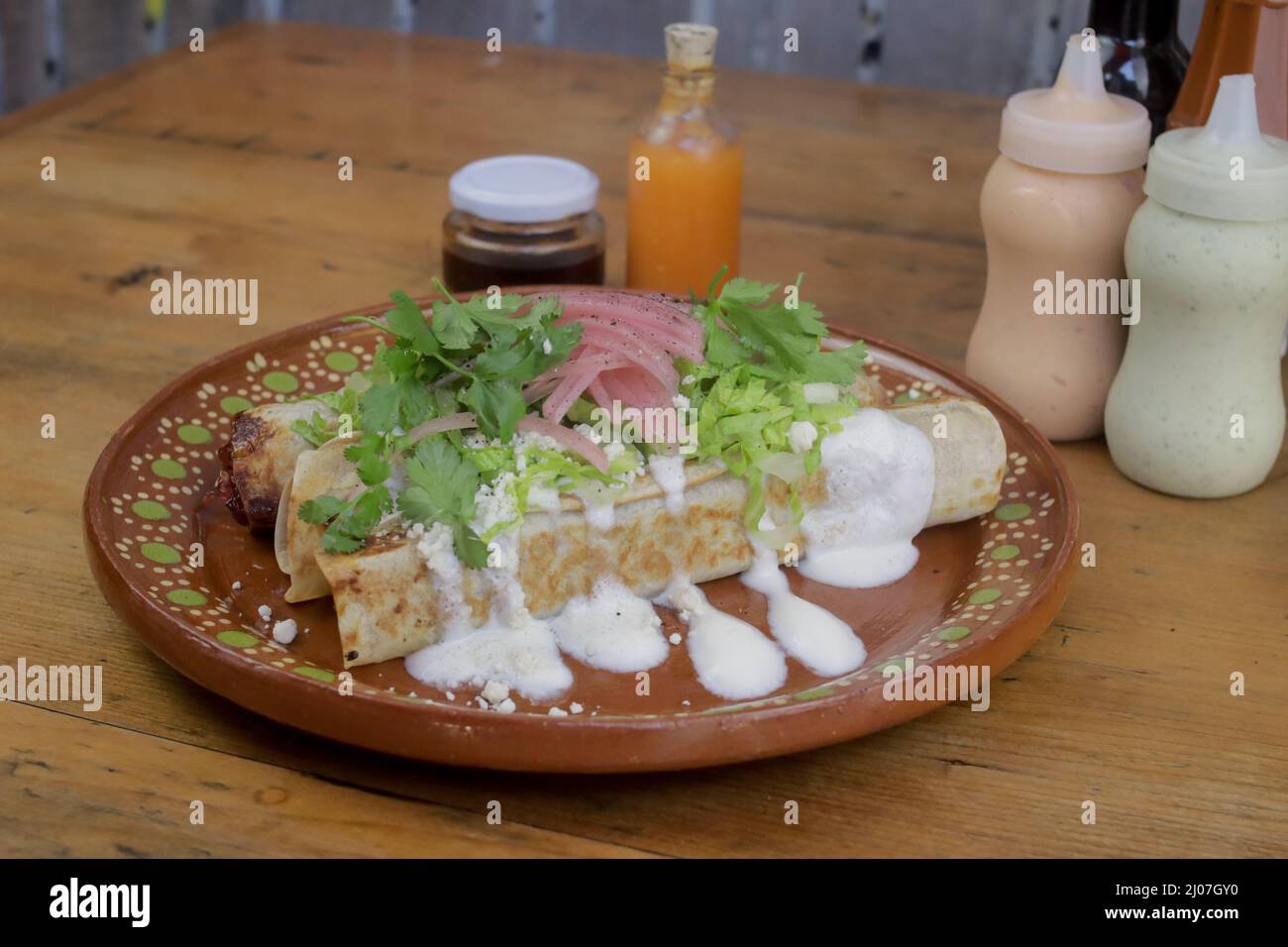 Closeup of the flour tortilla burrito with the sauces on the wooden ...