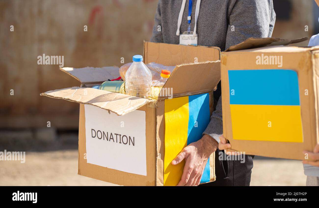 Close up photo of volunteer carrying box with humanitarian aid for ...
