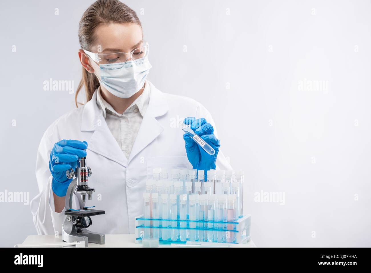 Female microbiologist in protective gloves and face mask holds ...