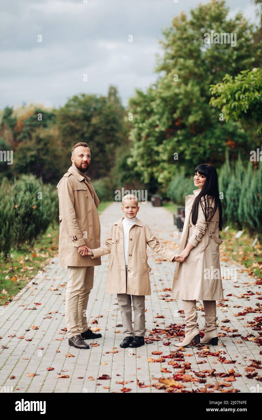 A happy family is walking in the park. Mom, dad and son are chatting ...