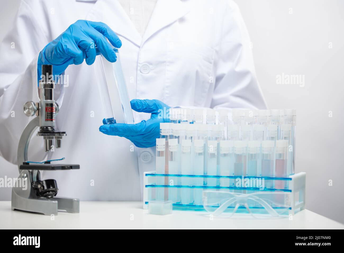 Female microbiologist or doctor in protective blue clothing holds ...