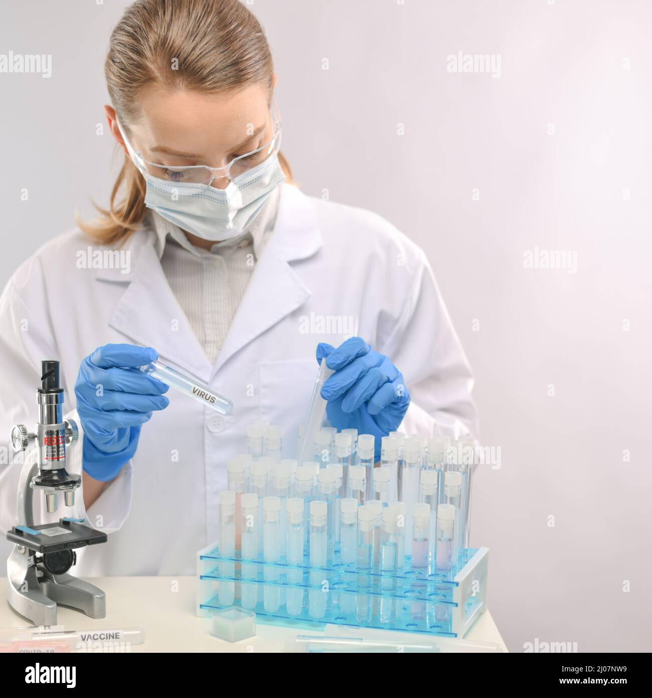 Female microbiologist in protective blue gloves puts biological tubes ...