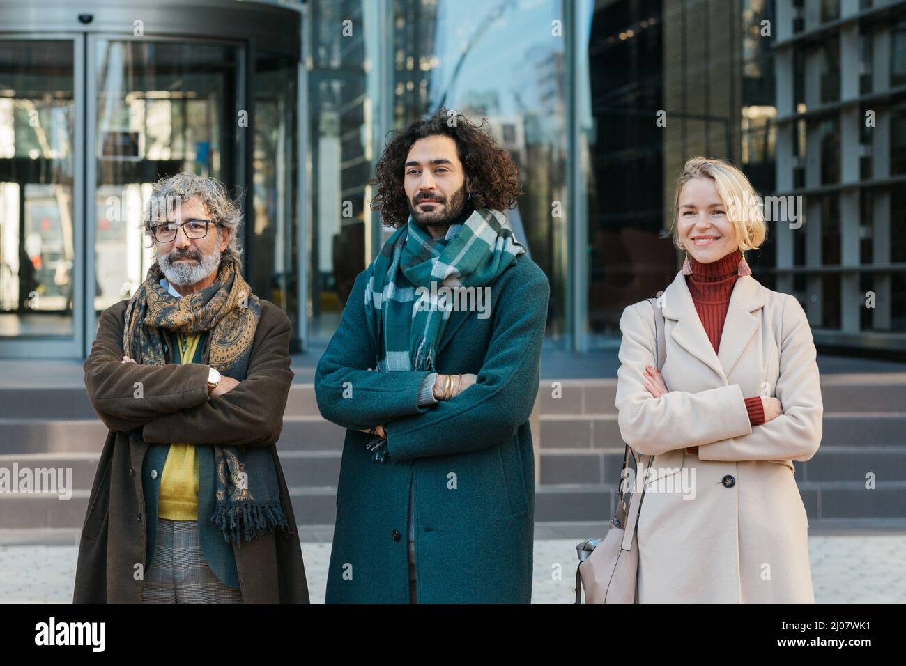 Three professional business people posing together outside of the ...