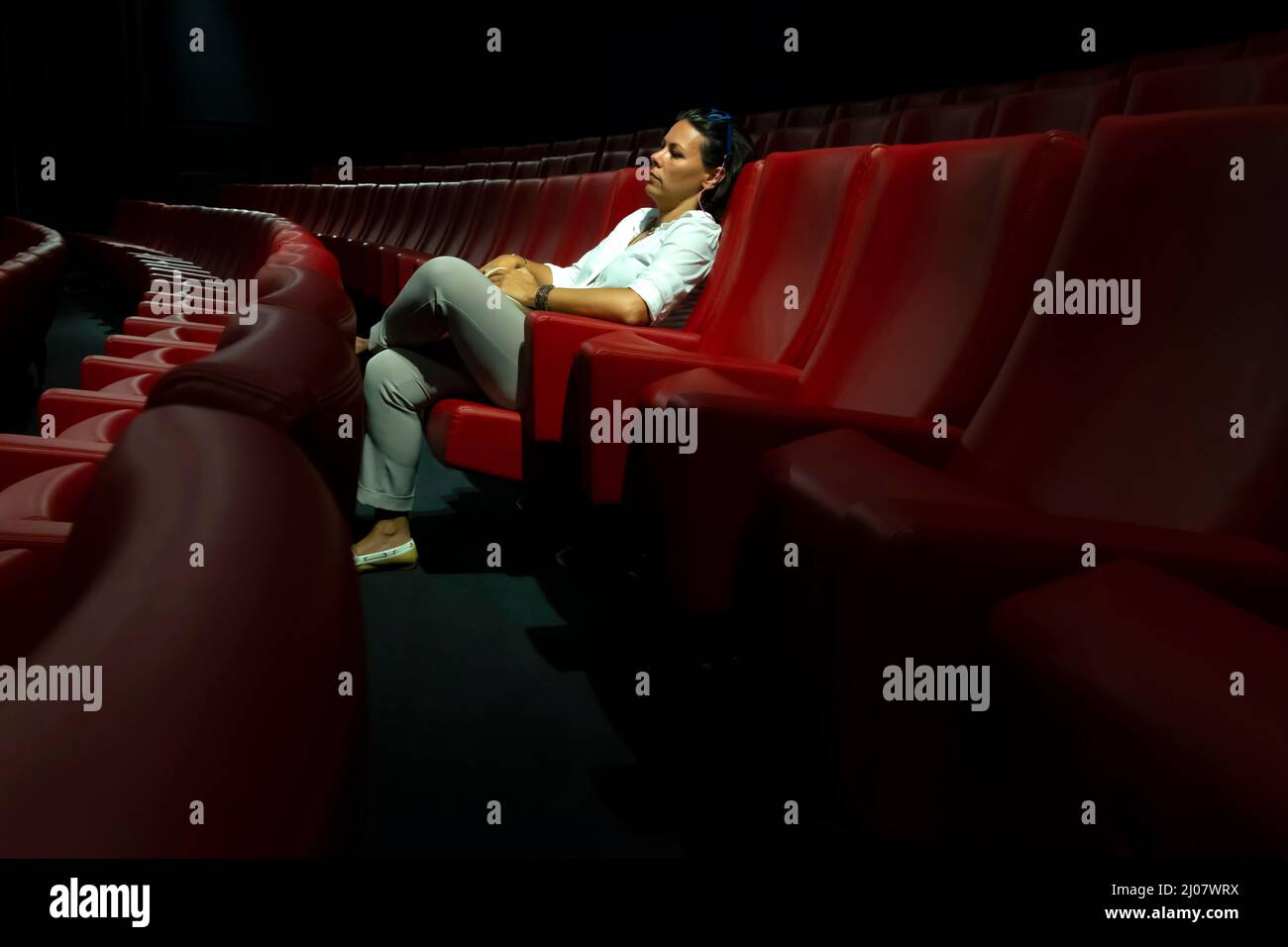 Woman Sitting Alone in Movie Theater. *** Local Caption *** Abundance ...