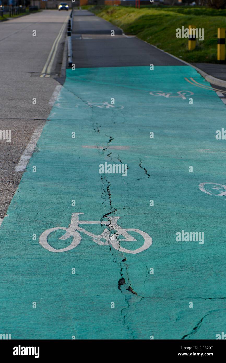 Colour cycle path with bike logo with cracks and damage to surface ...