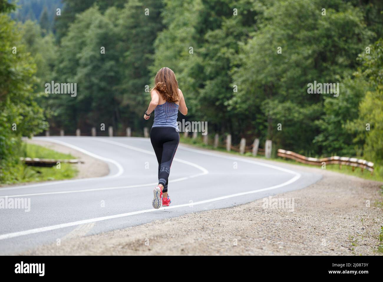 Runner woman running on the mountain road through the forest Stock ...
